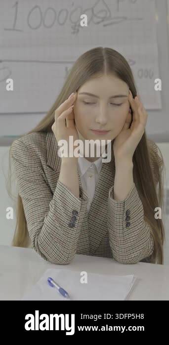 Overworked young woman massaging her temples due to a headache from ...