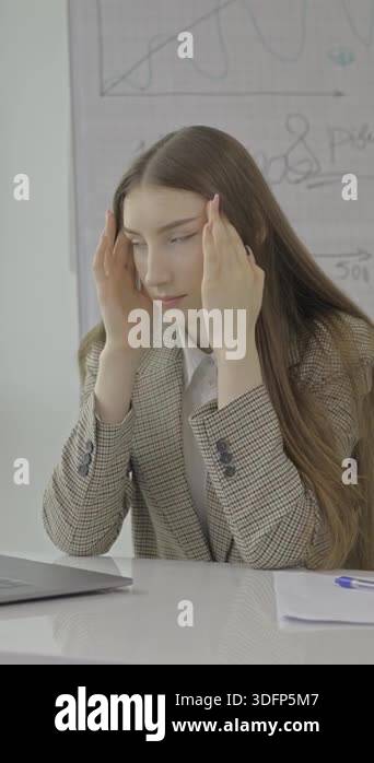 Overworked female employee massaging her temples because of a migraine ...
