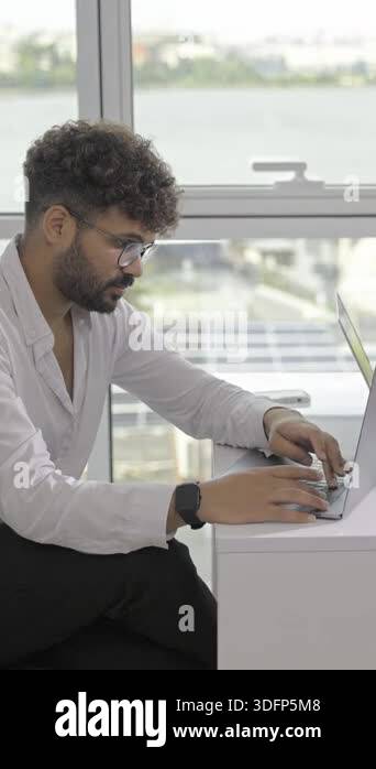 Focused businessman in glasses typing on a laptop computer keyboard ...
