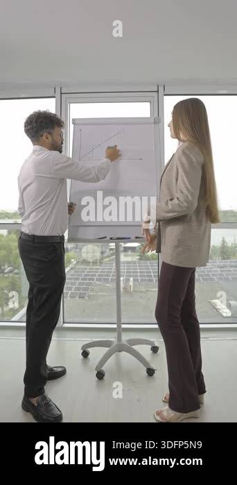 Young businessman presenting a project, drawing a graph on a flipchart ...