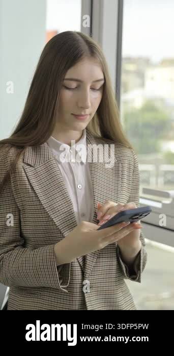 Confident female professional in a suit typing a message on her mobile ...