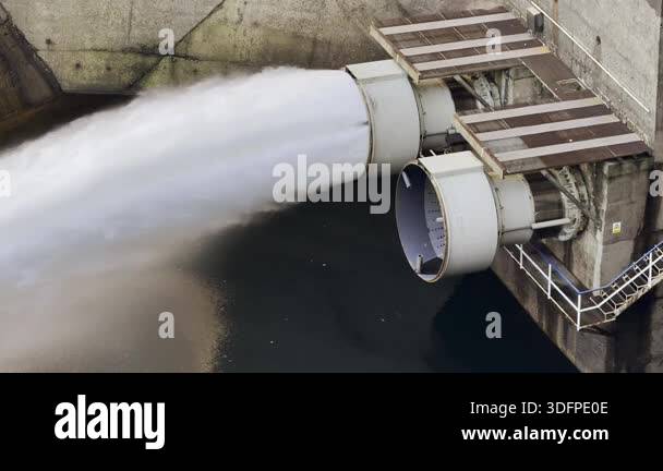 spraying water under pressure from a dam pipe at a hydroelectric power ...
