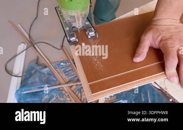 Professional handyman using an electric jigsaw to cut a laminate wood ...