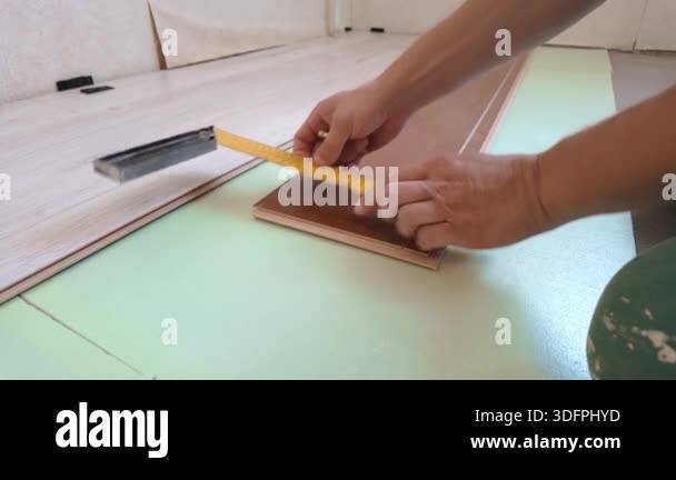 The craftsman's hands carefully measure the wooden laminate with a ...