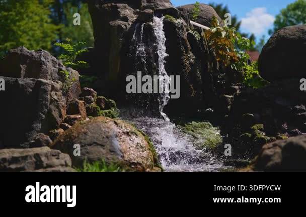 Small artificial waterfall flowing over dark garden rocks Stock Video ...