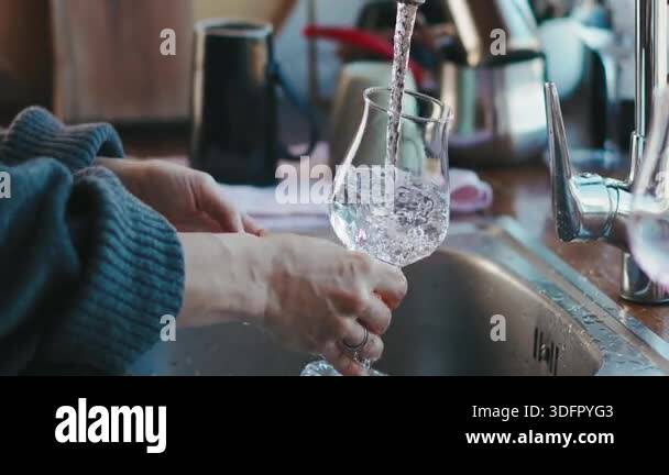 Close-up of female hands washing a wine glass in the kitchen sink ...