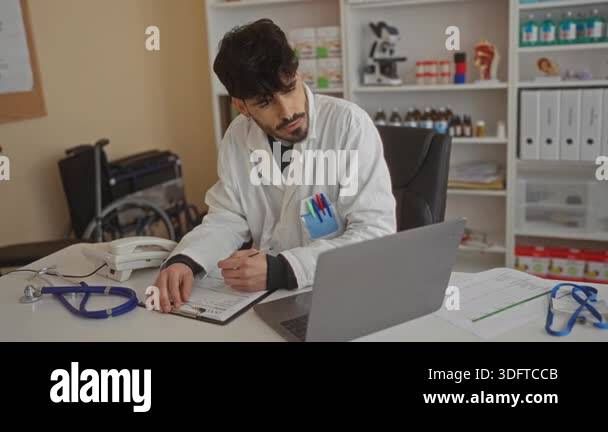 Doctor writing notes in clinic office with stethoscope and laptop on ...