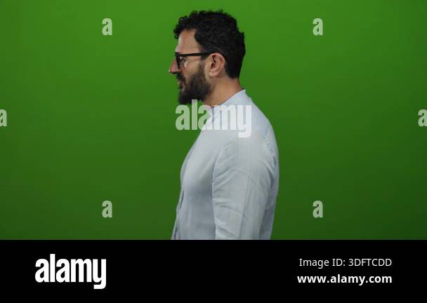 Hispanic man with beard and glasses in profile standing against a ...
