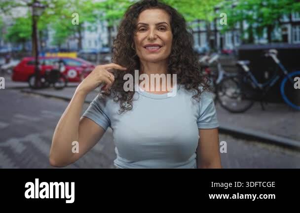 Woman pointing finger to chest in light blue shirt on busy urban street ...