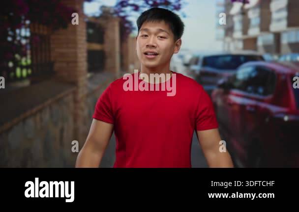 Young man in red shirt makes large gesture enthusiastically on city ...