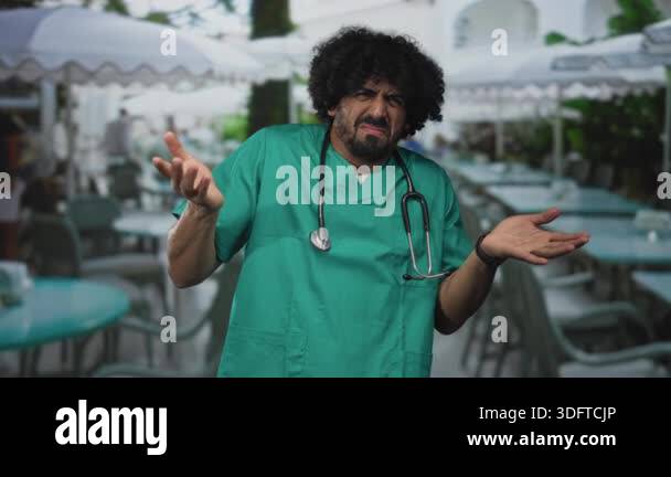 Man doctor in green scrubs with stethoscope shrugging hands palms up on ...