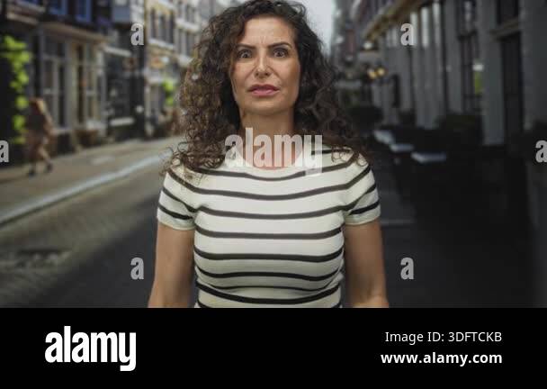 Young hispanic woman frames face with hands on street with raised ...
