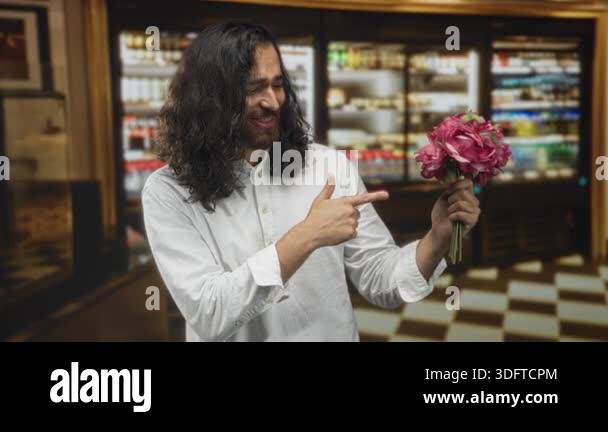 Man points finger and holds pink bouquet in restaurant with checkered ...