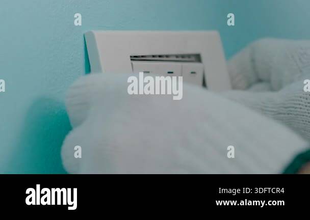 Close-up hand of man wearing cloth gloves and closing light switch ...
