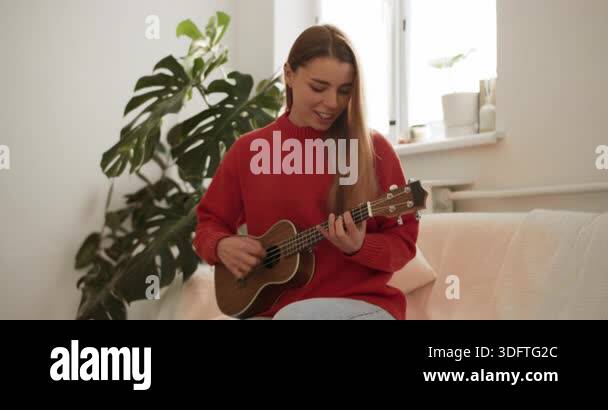 Cheerful female musician practicing on her stringed instrument in a ...