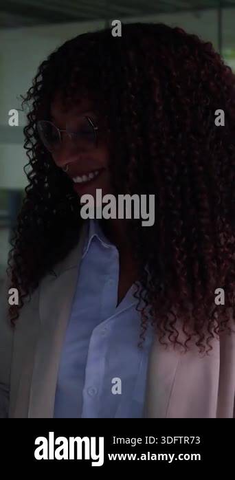 Vertical. African professional walks through a glass-fronted office ...