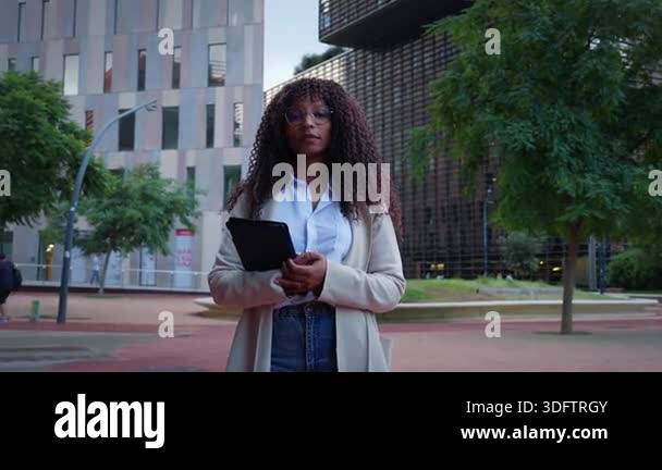 Young African woman in glasses holds a tablet and serious faces looking ...