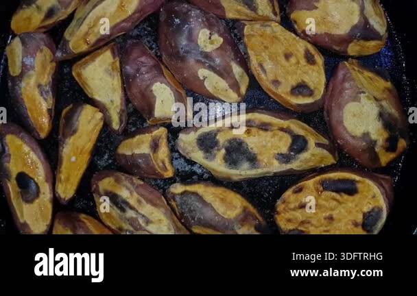 A top-down POV of oven-roasted chunky sweet potatoes rotating as they ...