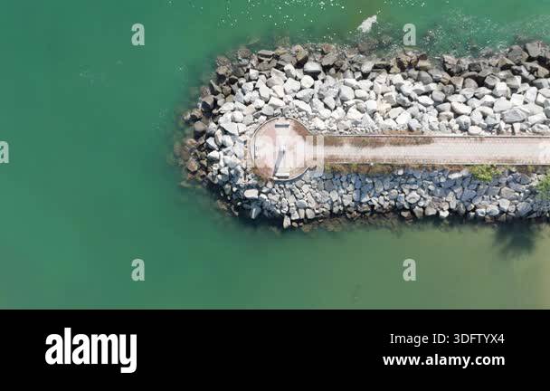 Drone shot of a stone breakwater and concrete walkway leading to a ...