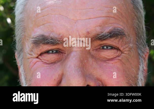 Blue eyes of elderly male blinking and looking into camera outdoor ...