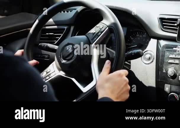 Male arms holds steering wheel while driving a motor car at city. Young ...