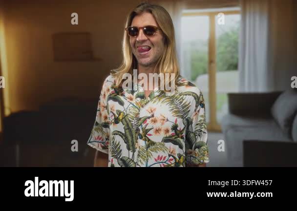 Blond man with long hair casually sticks tongue out wearing sunglasses ...