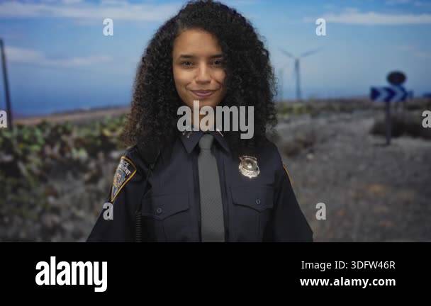 Young hispanic woman police officer in uniform stands before windmill ...
