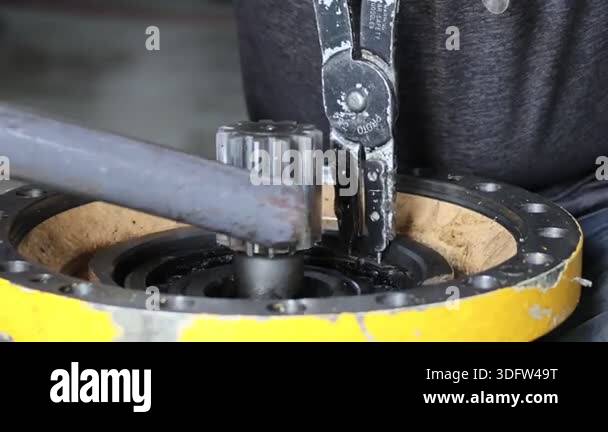 Technician using snap ring pliers to precisely install a retaining ring ...