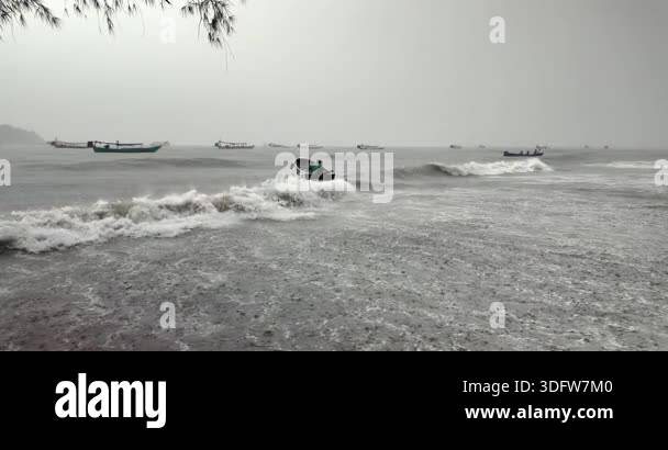 Person in a small boat being tossed by a large wave during a stormy day ...