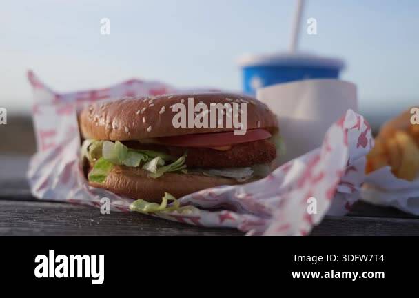 Tallinn, Estonia - April 2, 2025: Enjoying a burger, soft drink, and ...