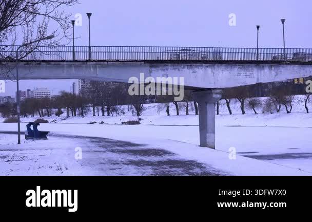 Pedestrians and a food delivery courier crossing a bridge over a frozen ...