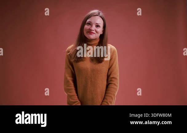Woman nodding politely while listening and reacting on brown background ...