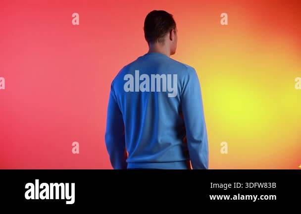 Man in blue sweater standing still during rotating studio against neon ...