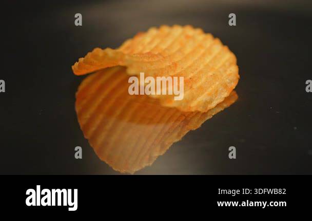 Single crispy golden potato chip rotation in slow motion. Fast food and ...