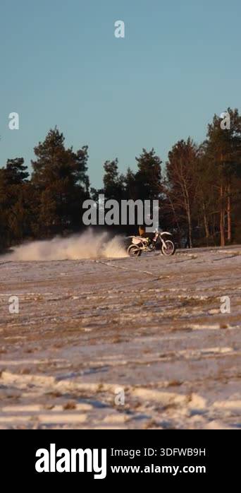 A dynamic view of a rider on a dirt bike racing across a snow dusted ...