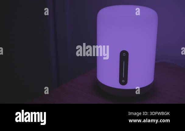 Smart lamp standing on a table smoothly changing colors, modern ...