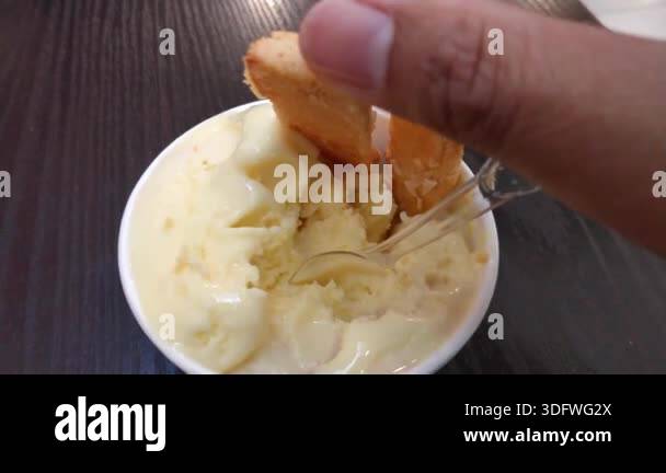 enjoying an ice cream with biscuits in a bowls at wooden table ...