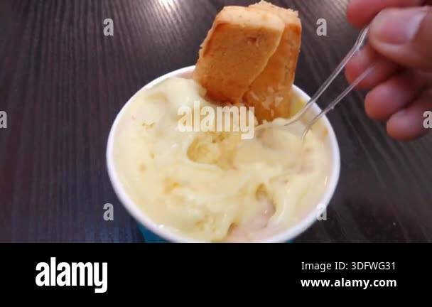 enjoying an ice cream with biscuits in a bowls at wooden table ...