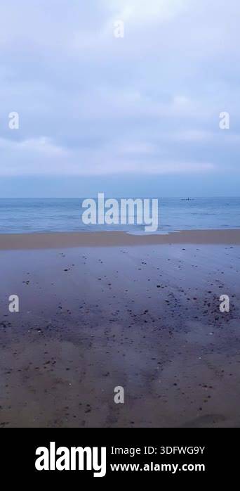 Low angle vertical shot of calm coastal surf water waves rolling on ...
