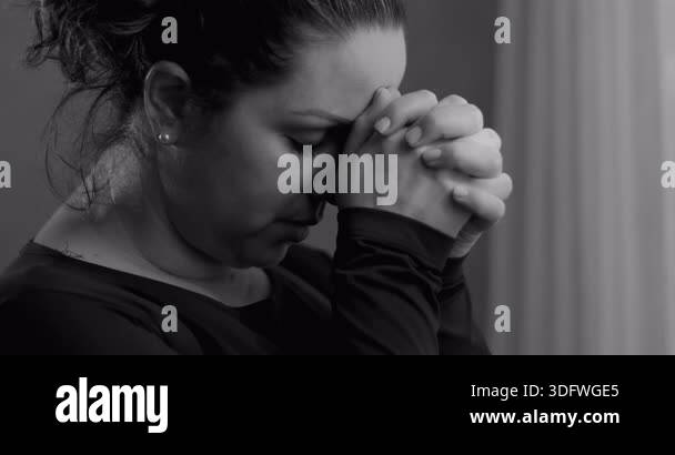 Woman clasps hands in black and white, expressing devotion, inner ...