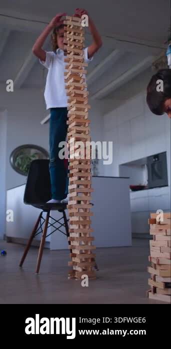 Child builds towering wooden block structure piece by piece expressing ...
