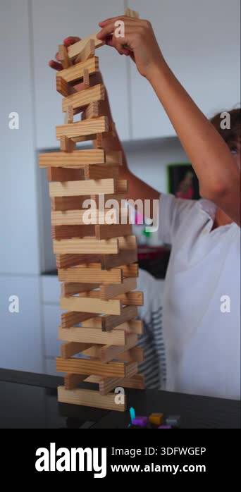 Child adds top piece to towering block structure expressing ...