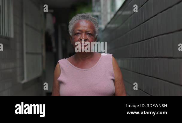 Senior woman looks toward camera in passageway, expressing calm ...