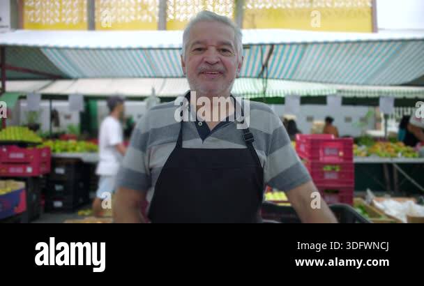 Senior man poses at outdoor produce market during workday, expressing ...