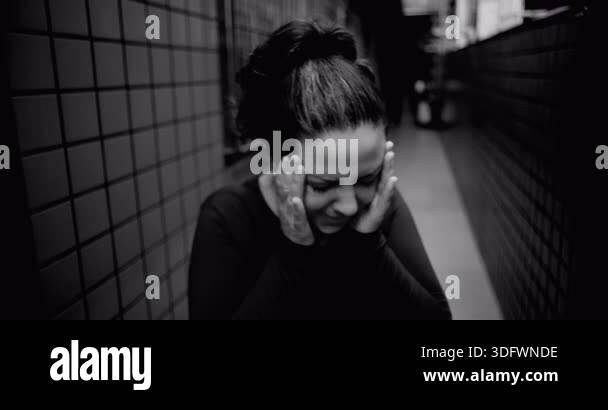 Woman clutching head in narrow corridor during mental health crisis ...