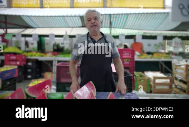 Senior man poses at outdoor produce market with fresh fruit display ...