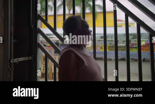 Senior woman gazes outside from home garage, expressing reflection ...
