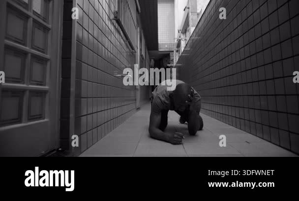 African American man kneels and leans forward in corridor, expressing ...