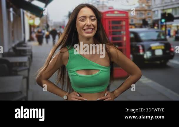 Woman pointing finger at camera on busy city street with red phone box ...