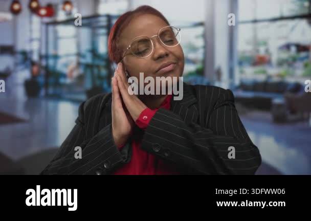 Woman with red hair wearing round glasses and a pinstriped jacket rests ...